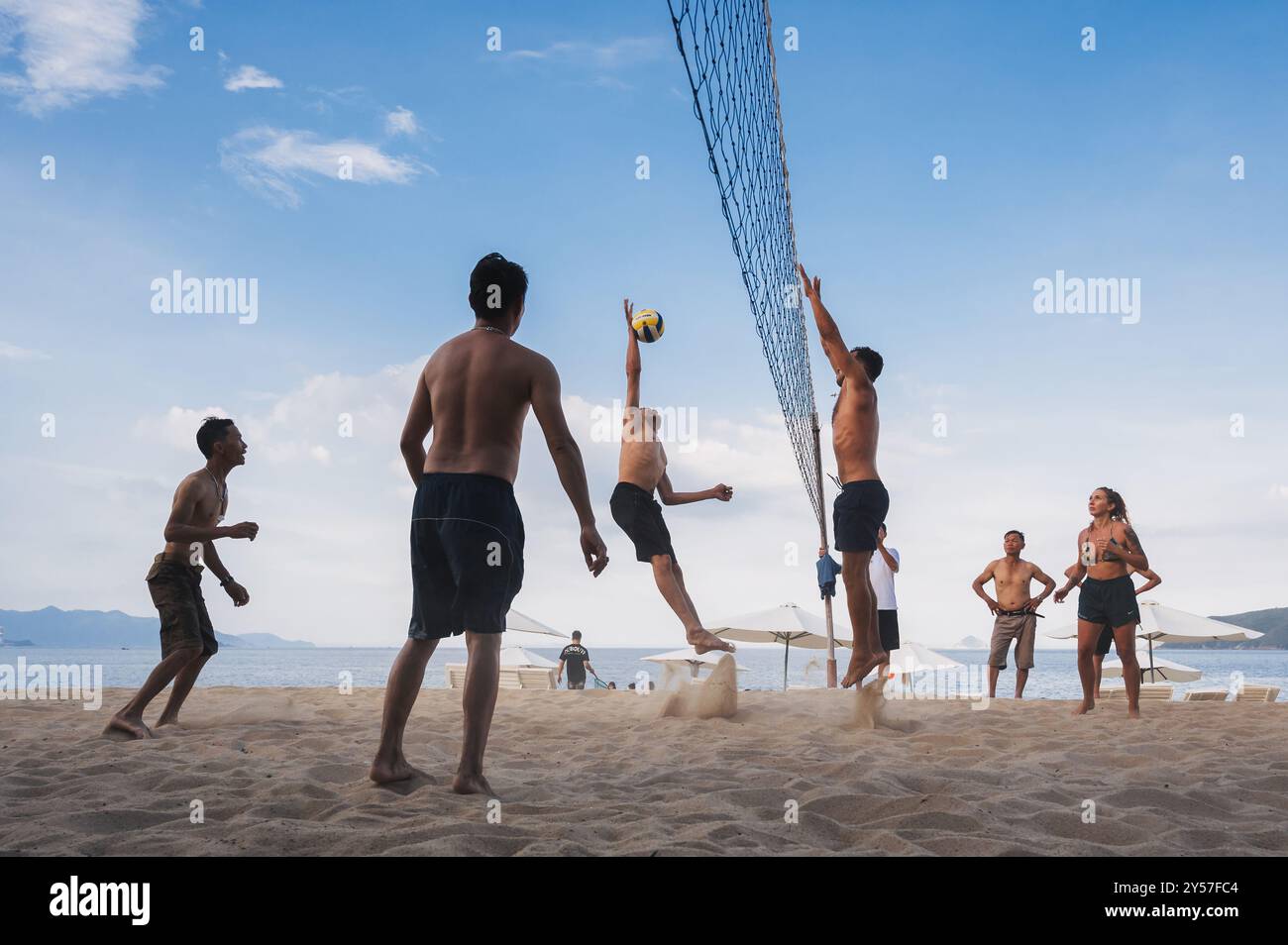 Multinational teams of people play beach volleyball on the beach by the ...