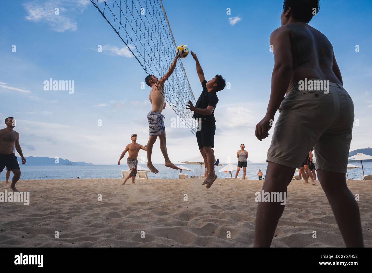 Teams with multinational players play beach volleyball by the sea in ...