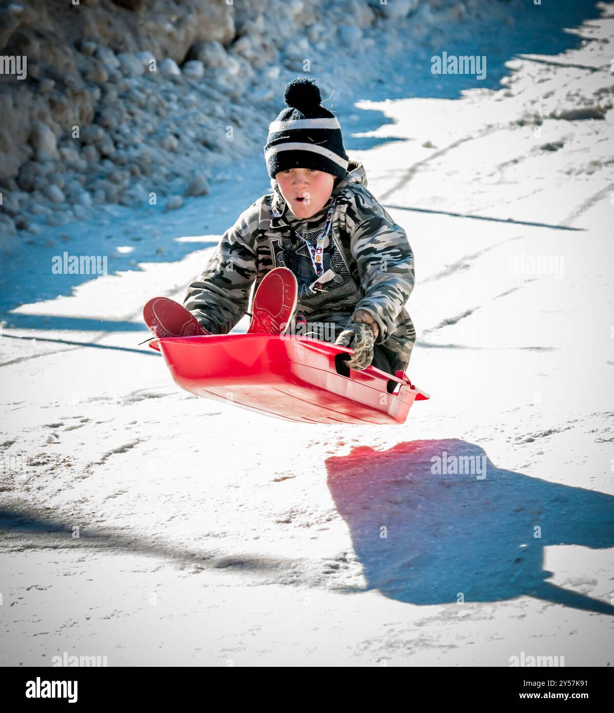 A little boy on his sled takes off into the air after hitting mound of ...