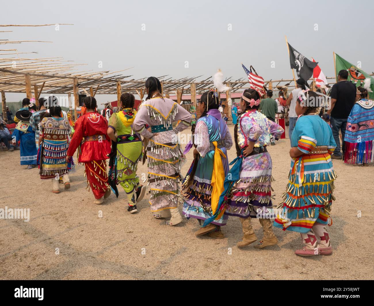 Line of young Native American women in jingle dresses dancing at a pow ...