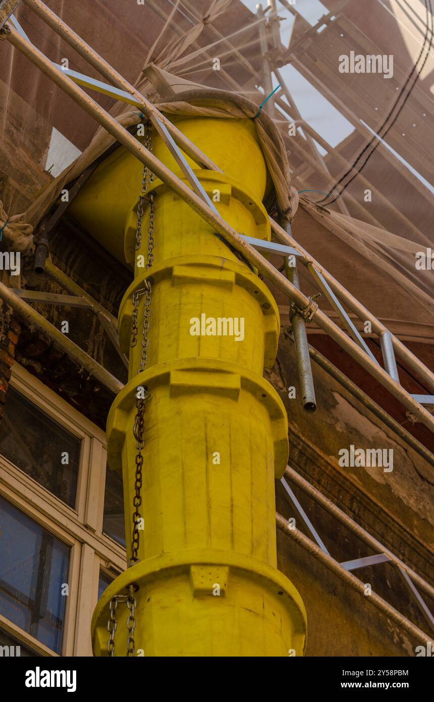 A yellow debris chute being used to remove construction waste from a ...