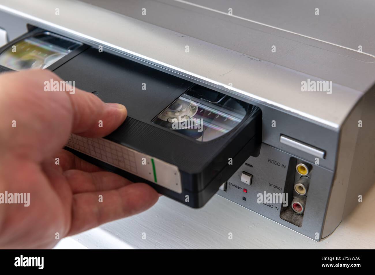 A person inserting a video cassette into a vintage video player Stock ...