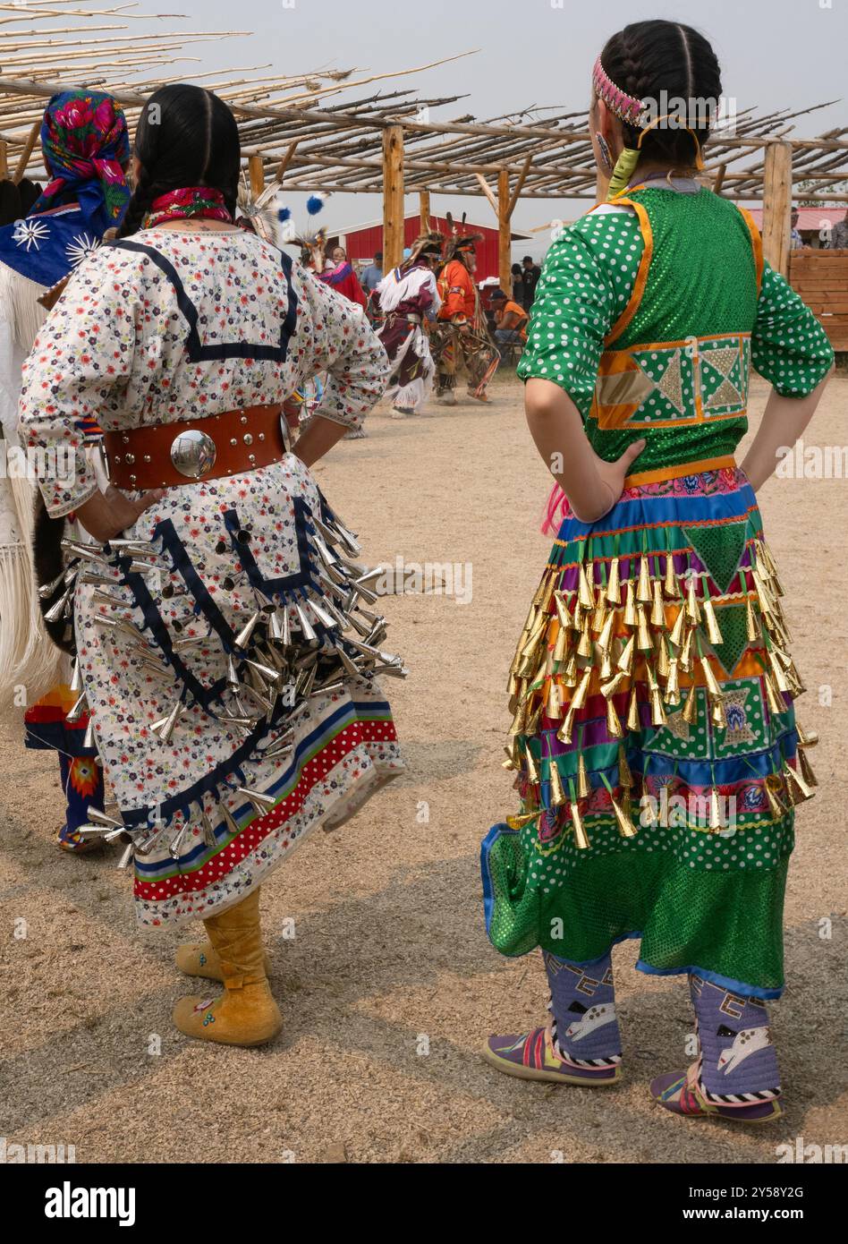 Two women wearing colorful jingle dresses dancing in a powwow in ...
