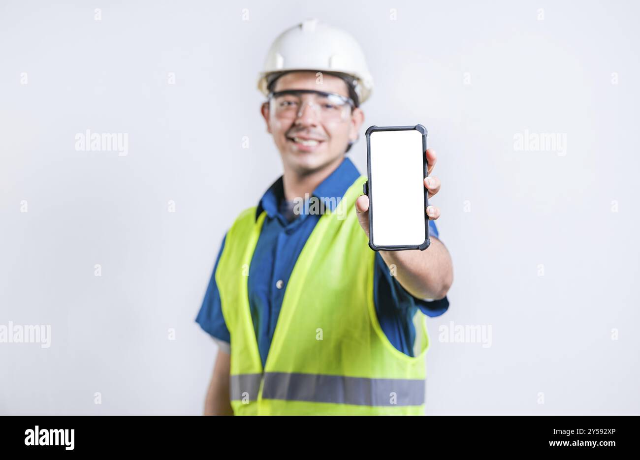 Smiling engineer showing cell phone screen isolated. Young construction ...