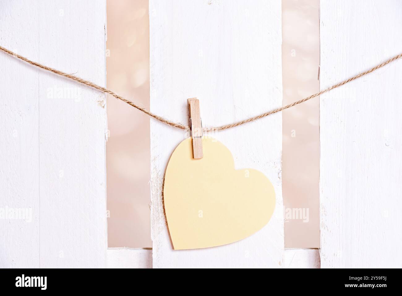 Paper note, heart-shaped, tied to a linen string with a wooden clip, on ...