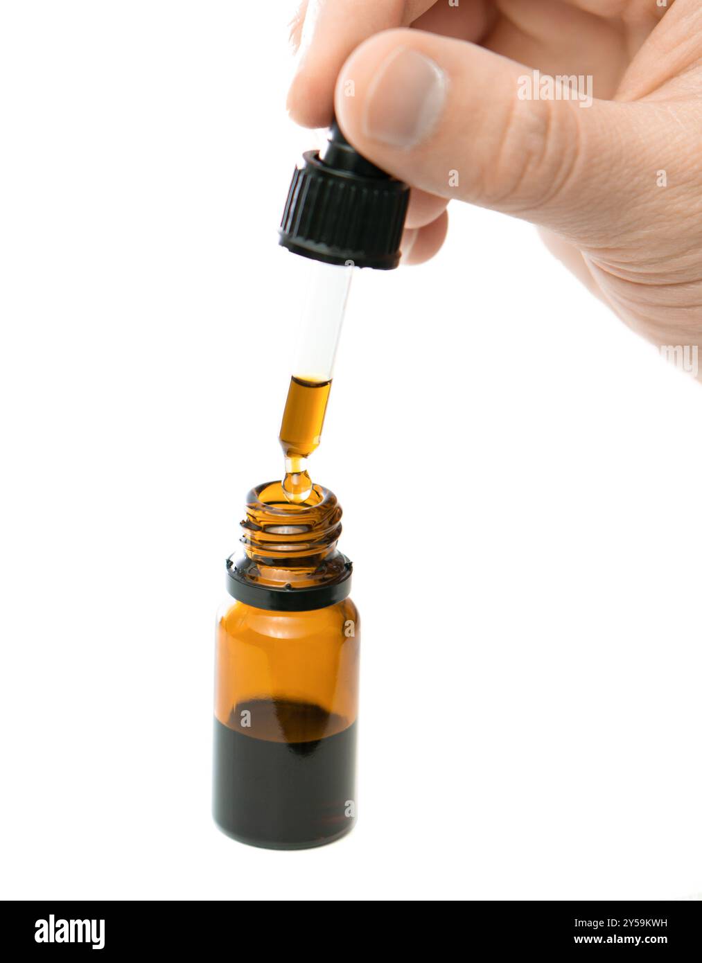 Hand dripping oil from a pipette in a glass bottle close-up isolated on ...