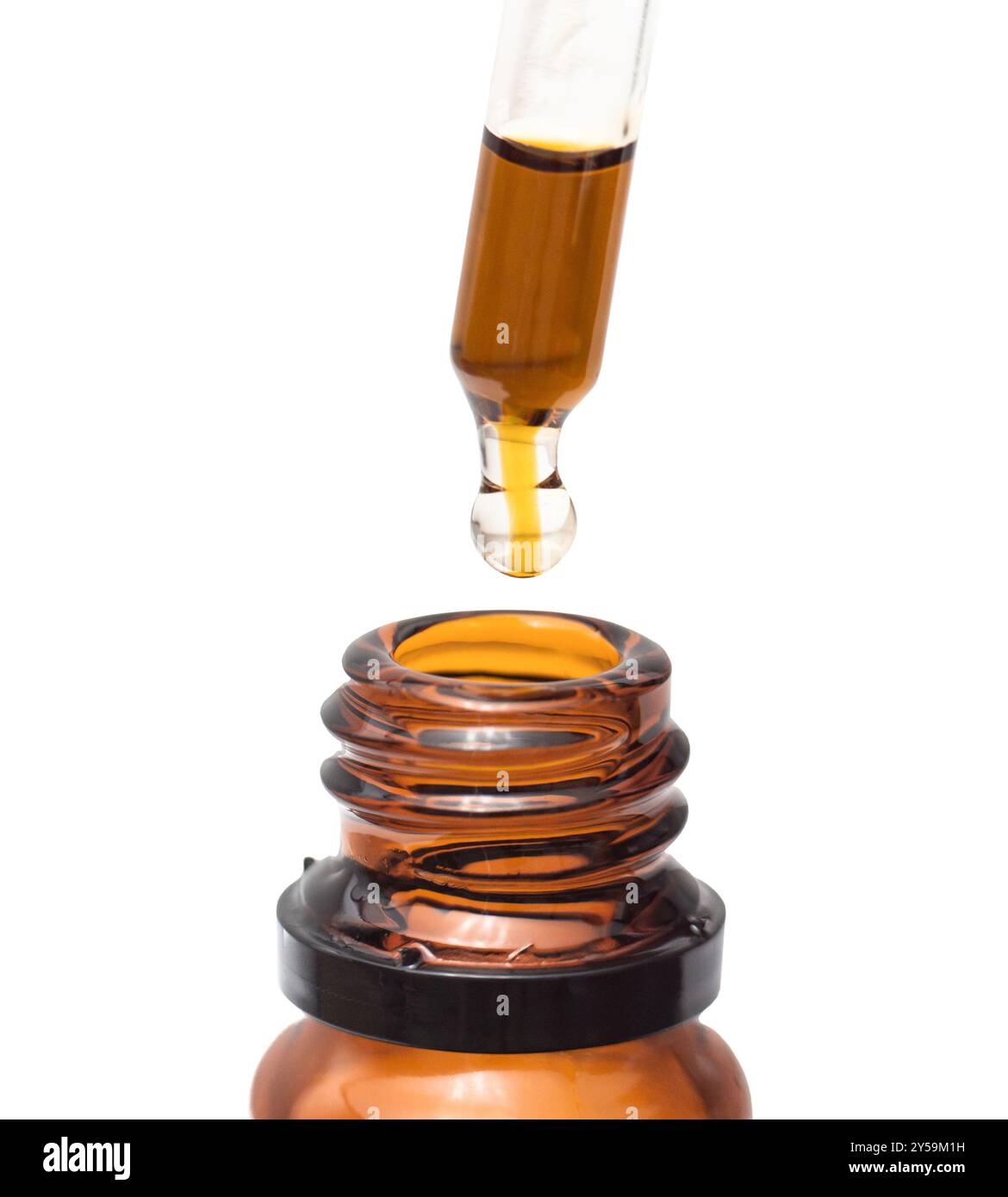 Dripping oil from a pipette in a glass bottle close-up isolated on ...