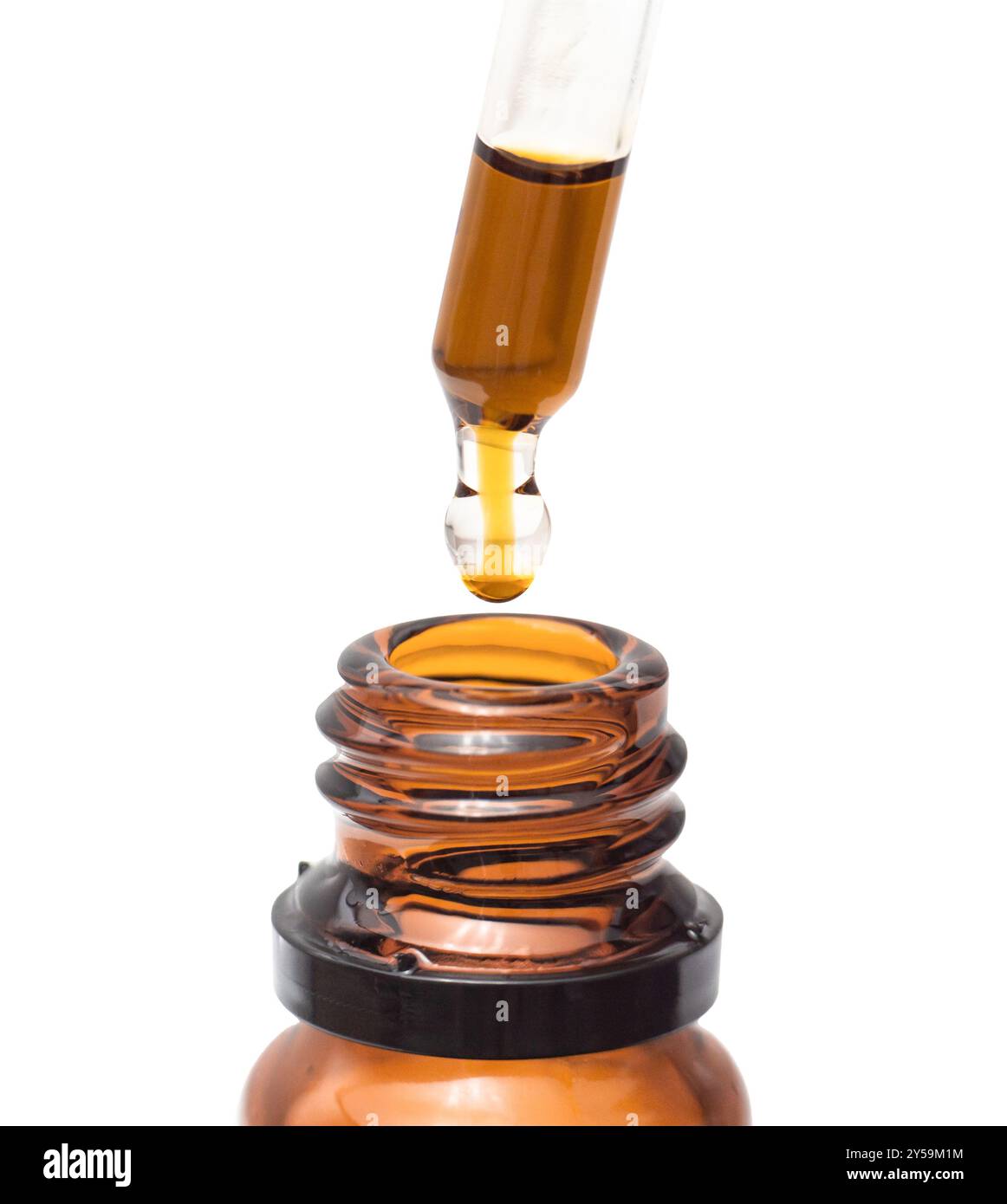 Dripping oil from a pipette in a glass bottle close-up isolated on ...