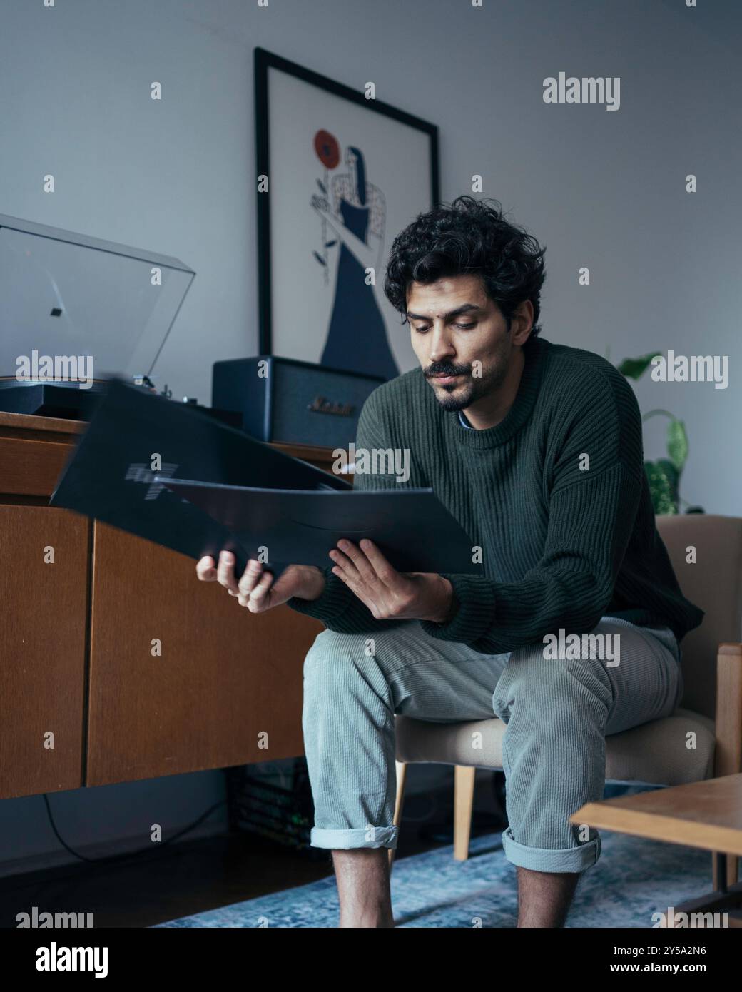 Young hipster cool looking man in apartment listening to music on vinyl ...