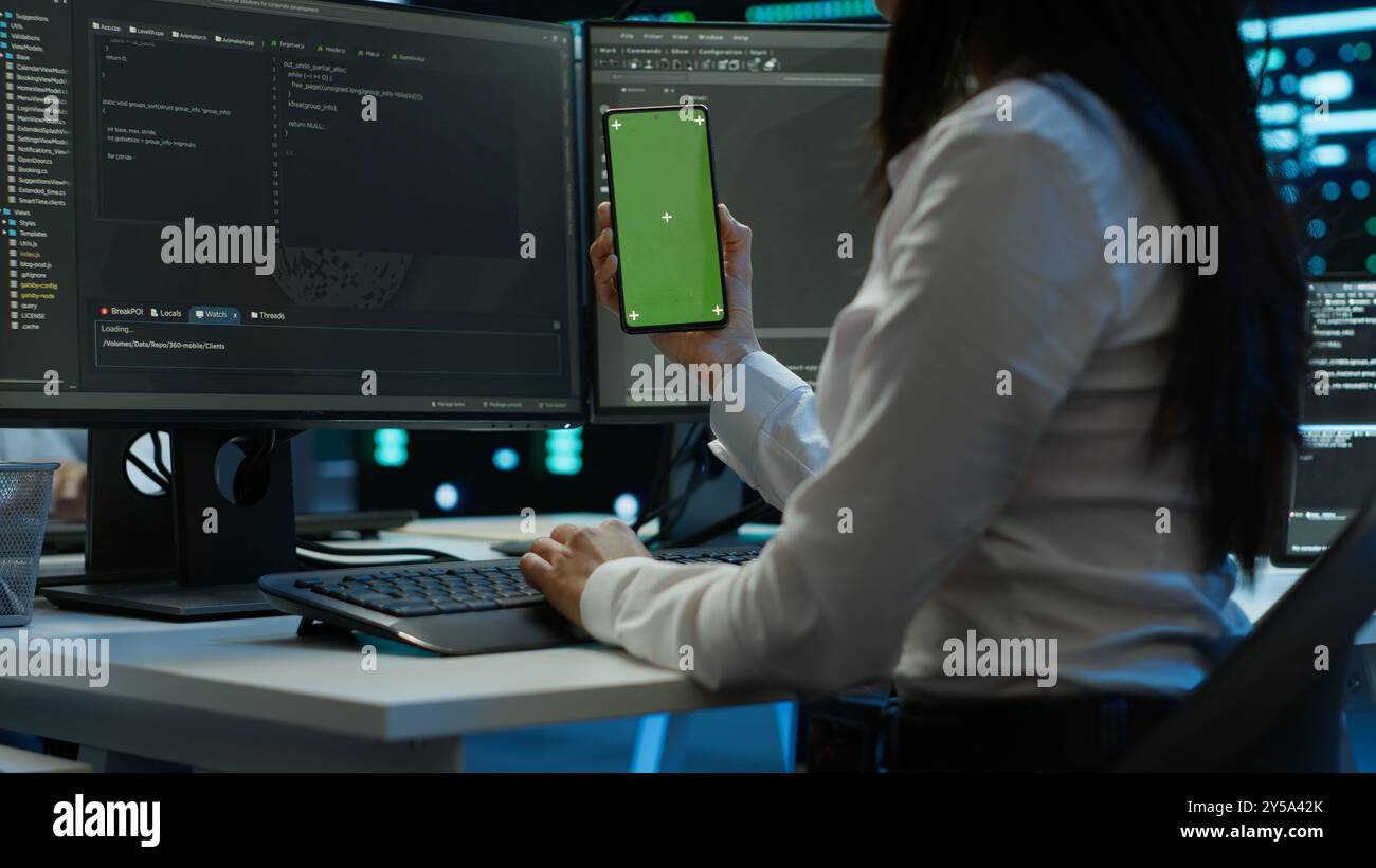 Worker overseeing data center using green screen mobile phone, ensuring system can handle ...