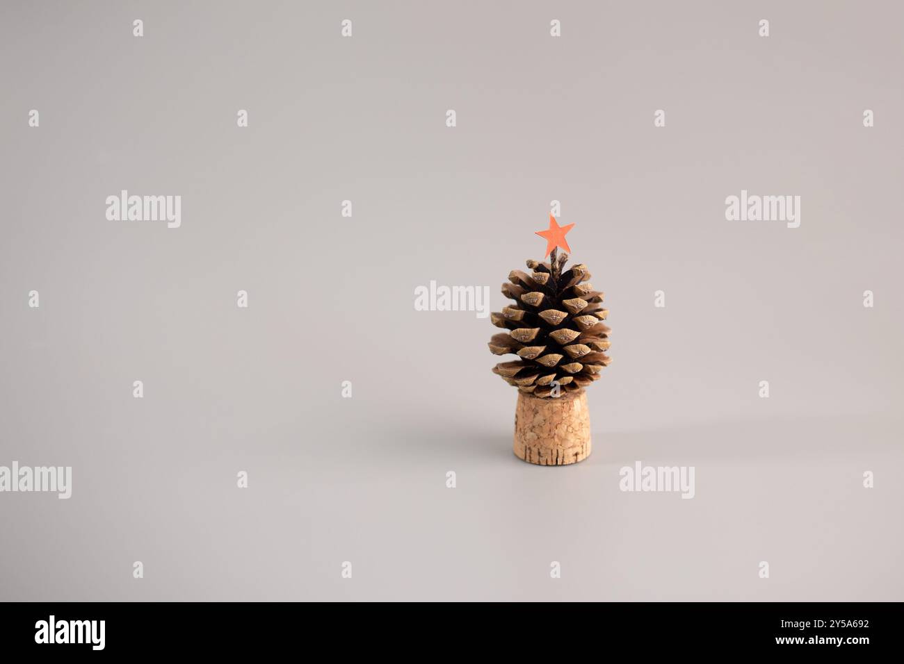 Upright pine cone with red star on cork base, solid light grey ...