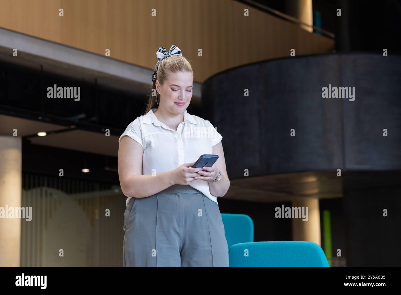 Using smartphone, businesswoman checking messages while standing in ...
