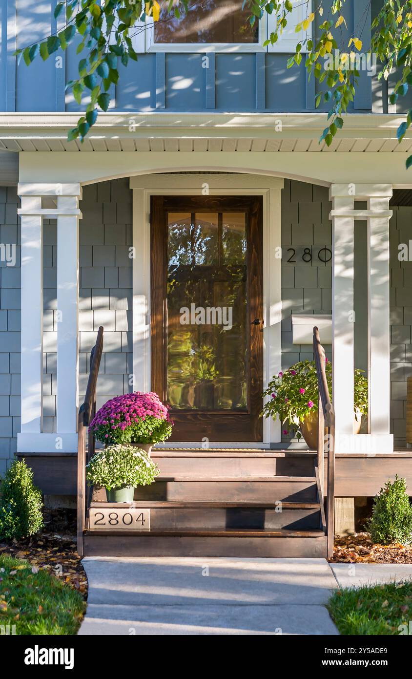Dappled sunlight hits front door and front porch of house with gray ...