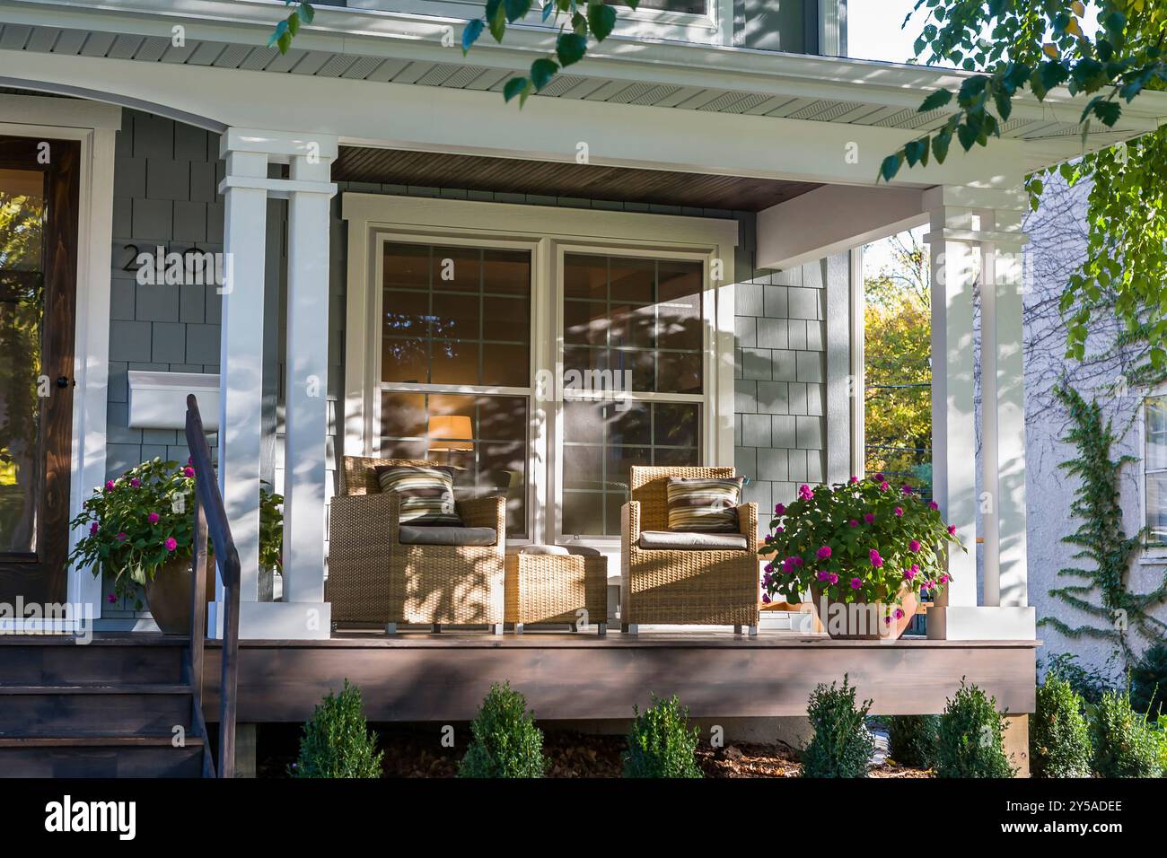 Sun dappled front porch with wicker chairs and flower pots Stock Photo ...