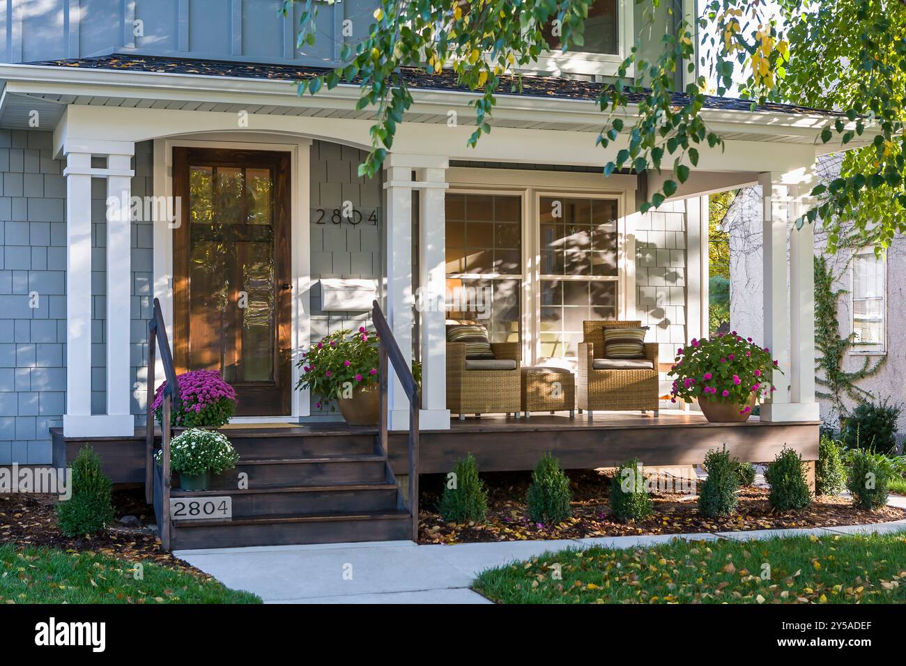 Dappled sunlight hits front door and front porch of house with gray ...