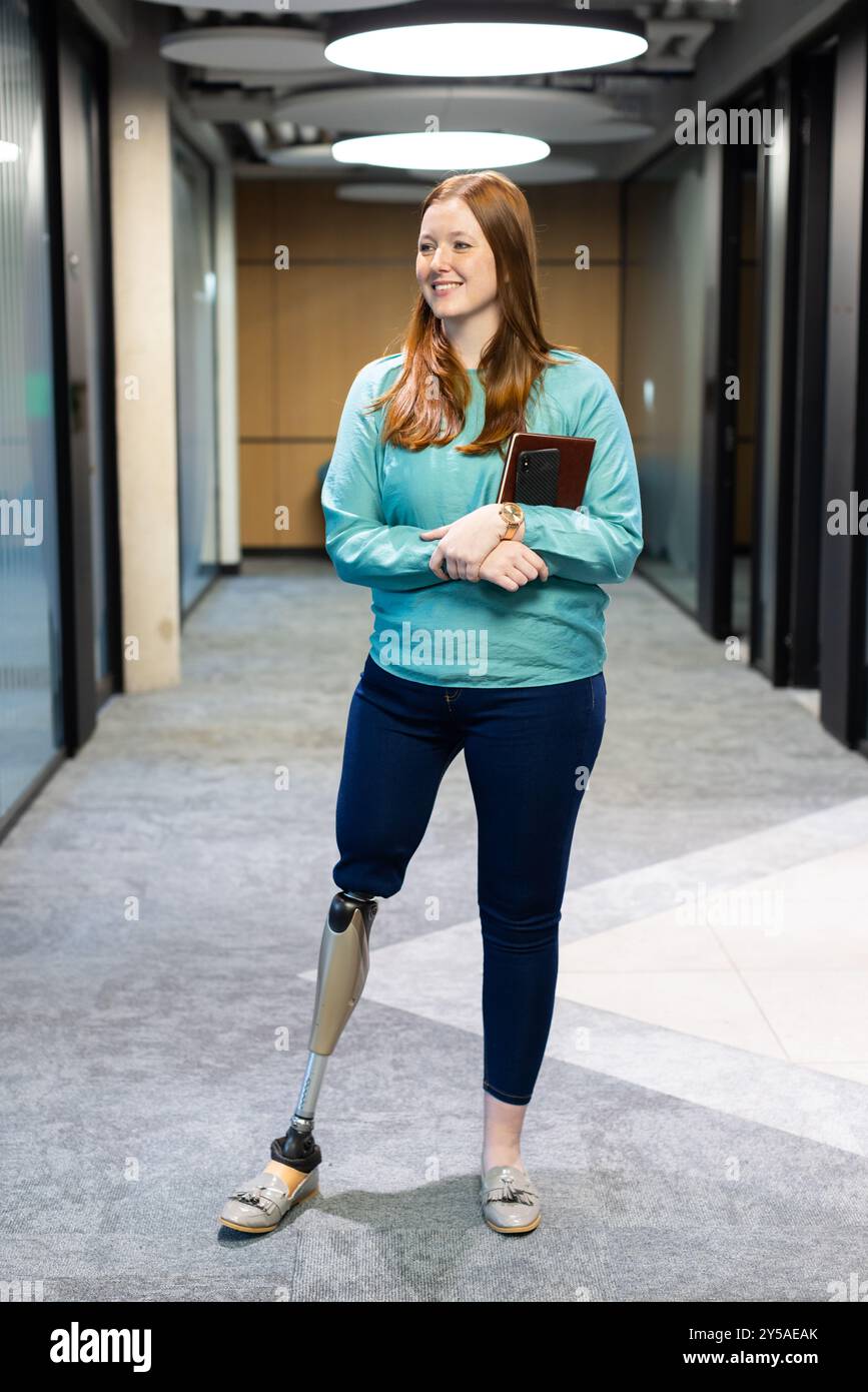 Walking in office, woman with prosthetic leg holding tablet and smiling ...