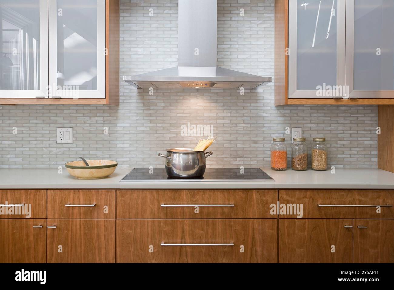 Modern kitchen showing smooth top cook top, vent hood and various items ...