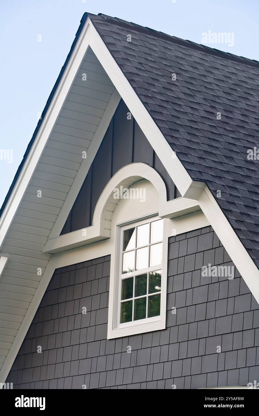 Peak of roof of gray shingle style house with white trim Stock Photo ...