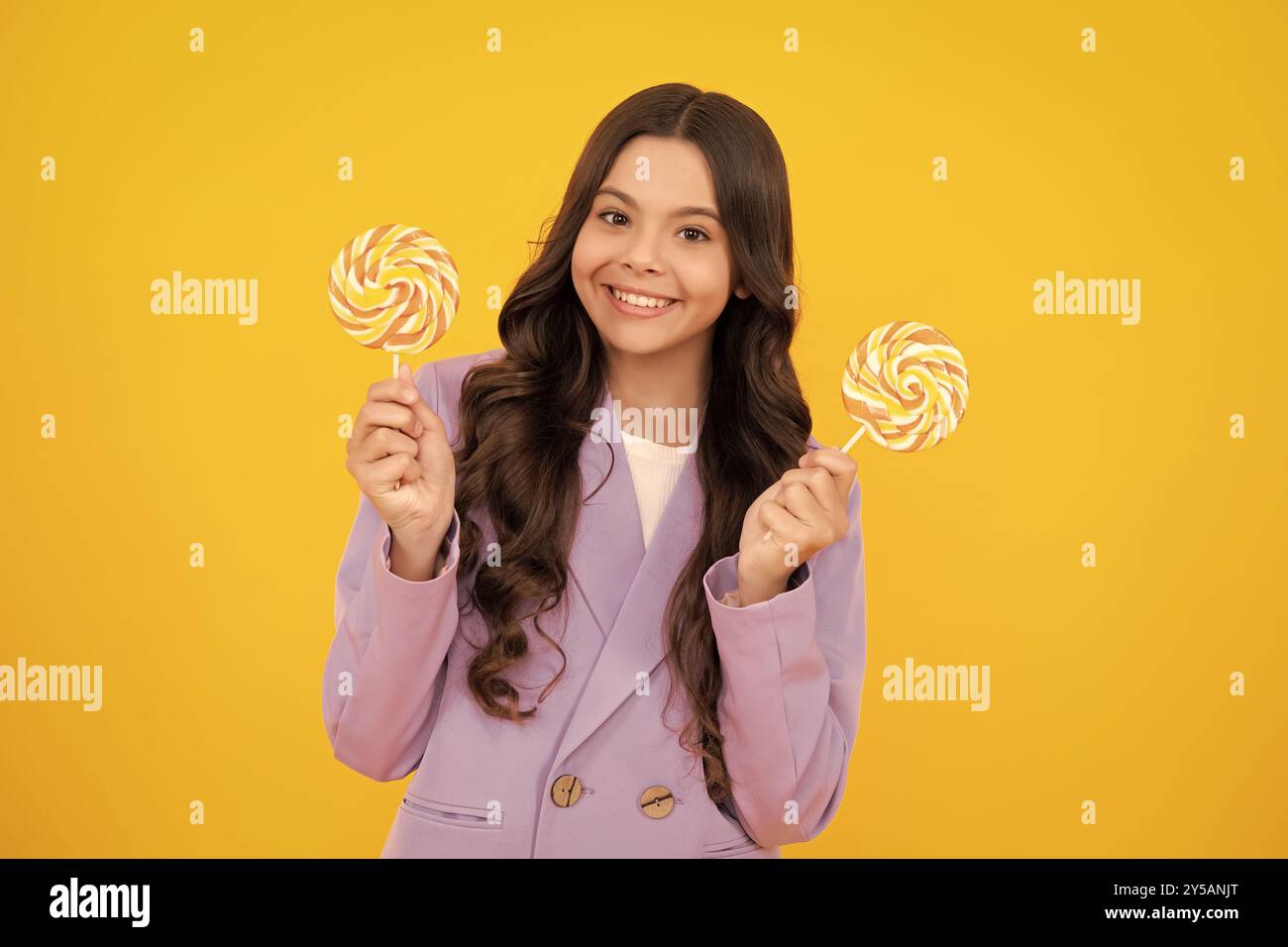 Cool teen child with lollipop over yellow isolated background. Sweet ...