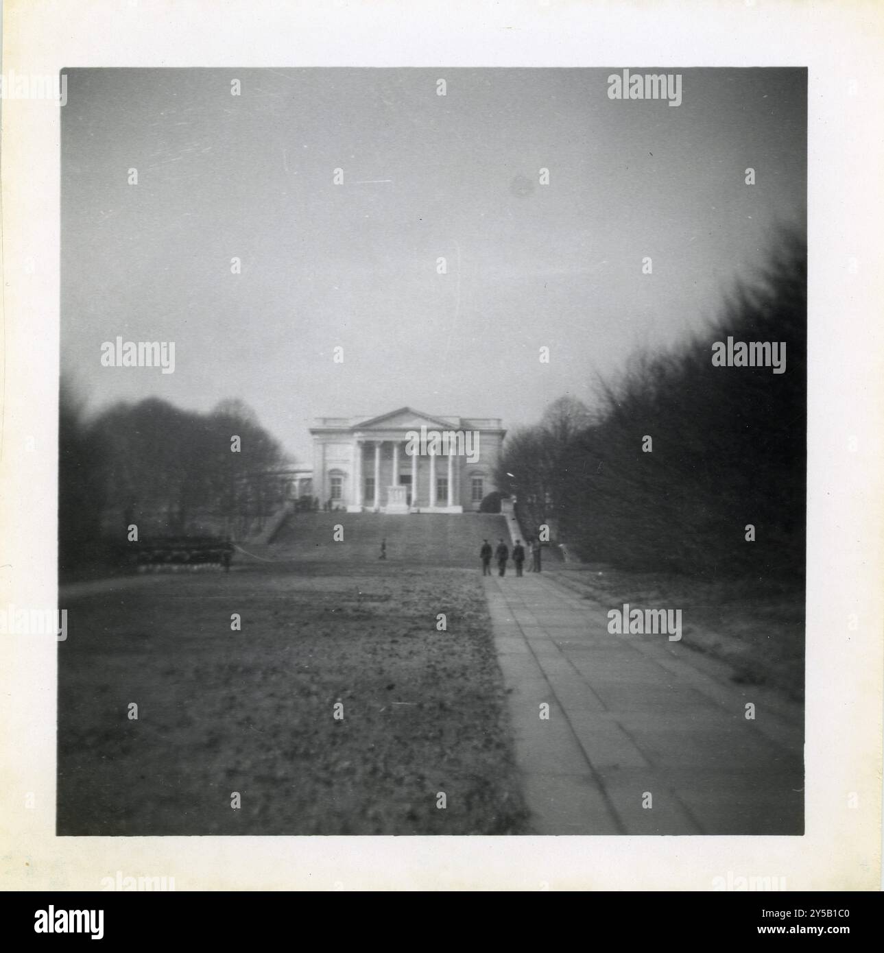 A grand neoclassical building stands at the end of a long walkway, its ...