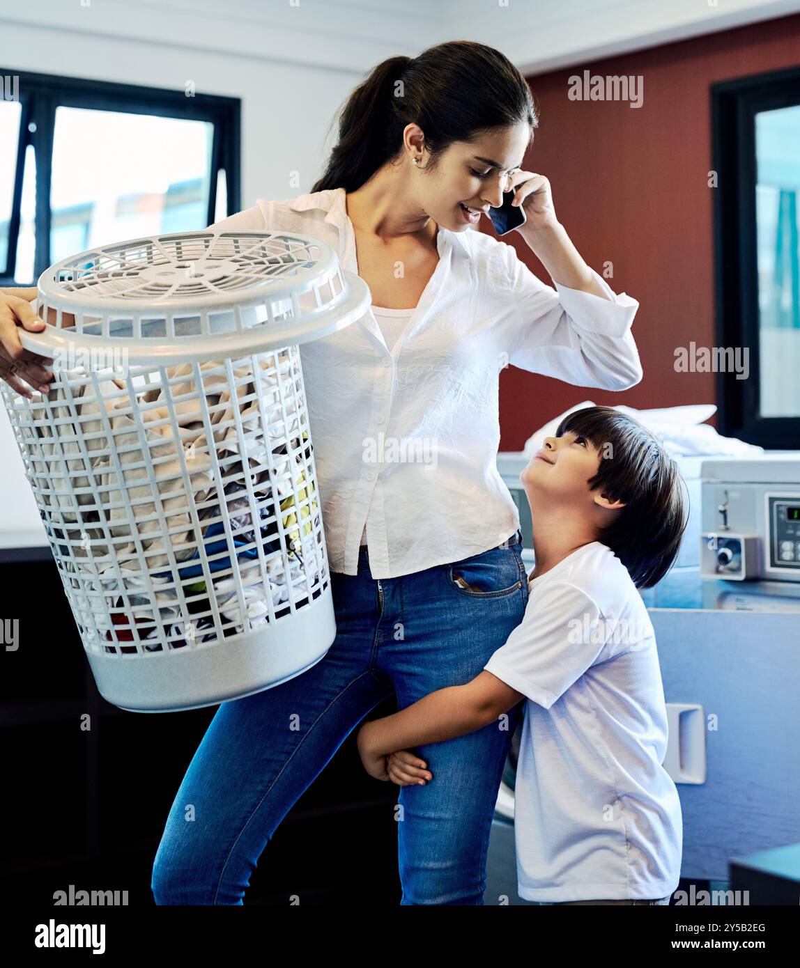Laundry, phone call and mother talking to child for cleaning, housework ...