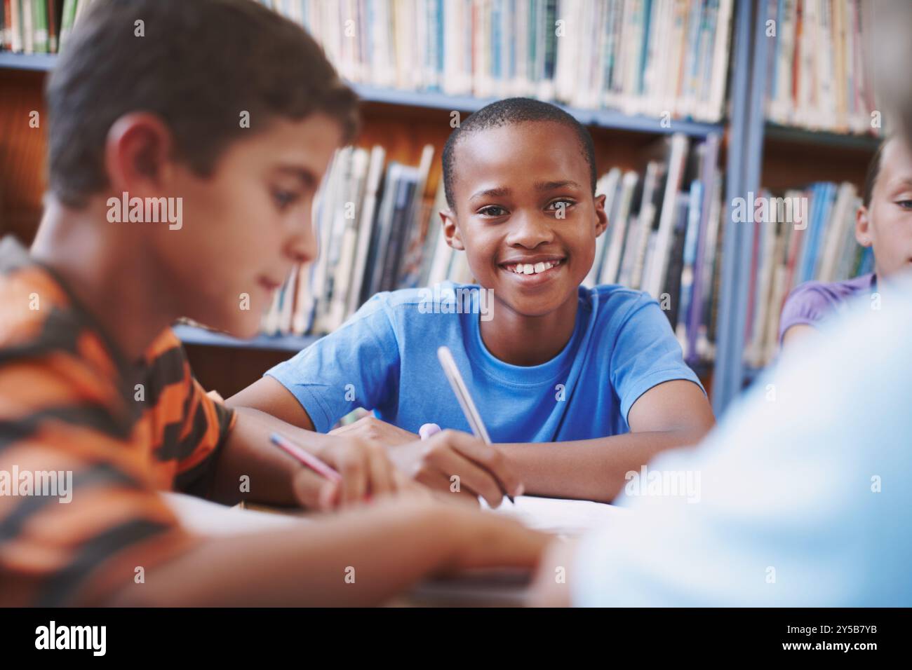 Black boy, writing and learning with books in library for assessment ...