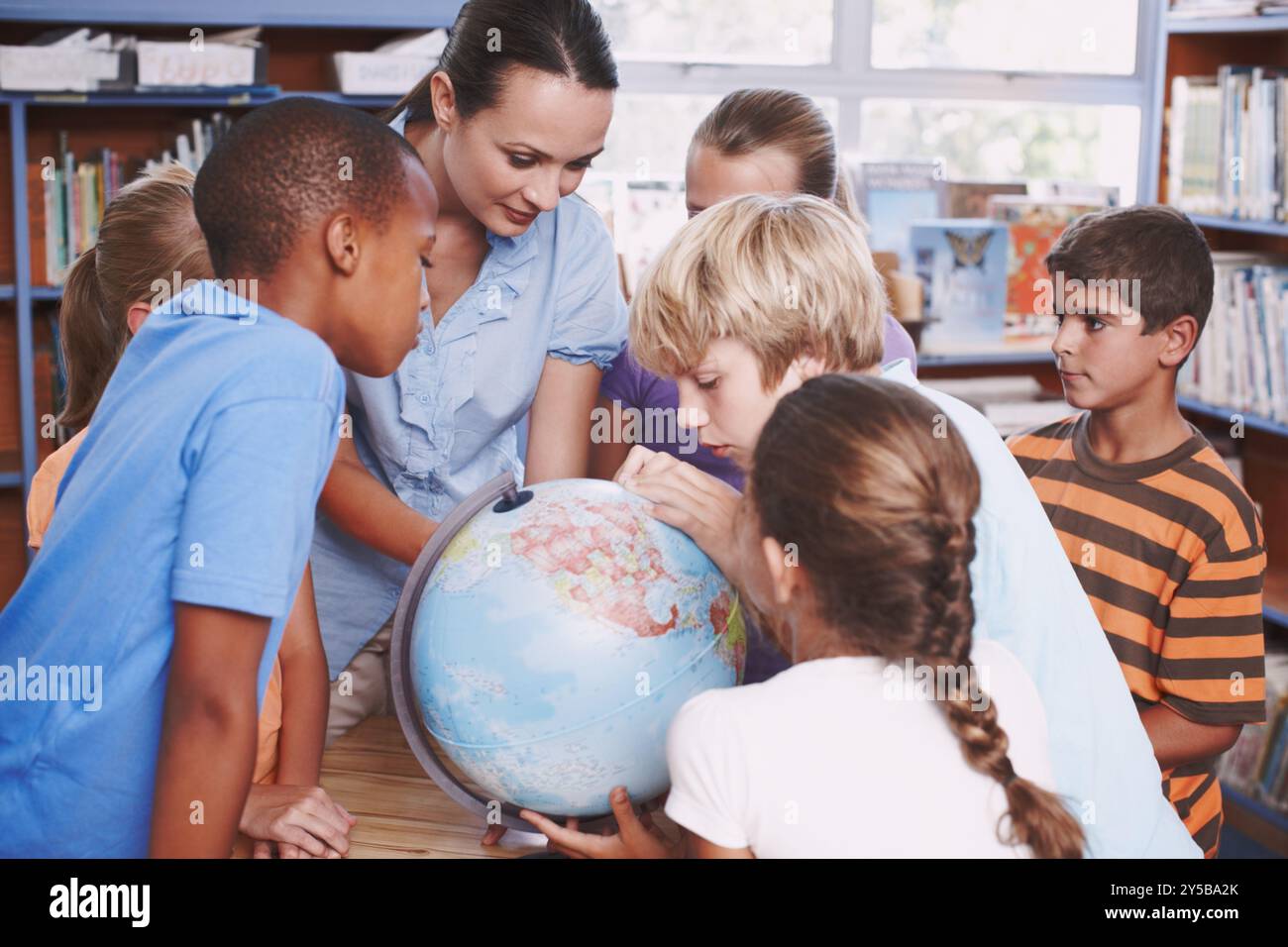 Children, teacher and map with globe in library for geography education, planet learning and and ...