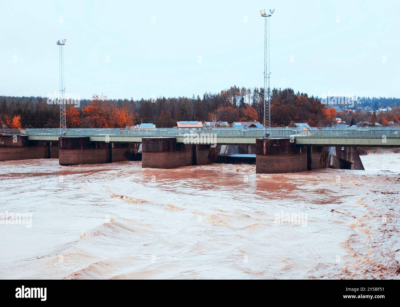 Overflowing river, bridge spanning turbulent waters, autumn-colored ...