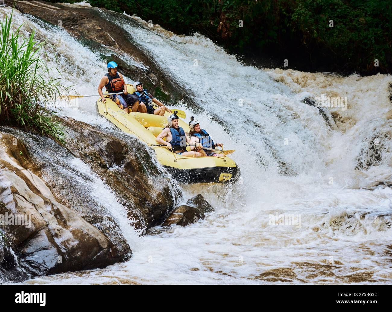 People, boat and rafting in waterfall for adventure, sports and holiday ...