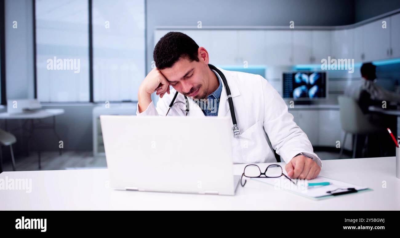 Tired Young Male Doctor Resting At Computer Desk In Hospital Stock ...