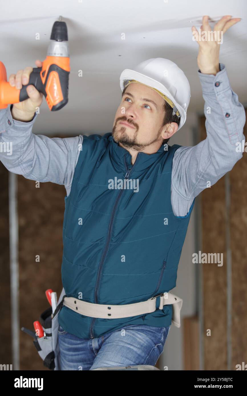 manual worker drilling ceiling with a drilling machine Stock Photo - Alamy