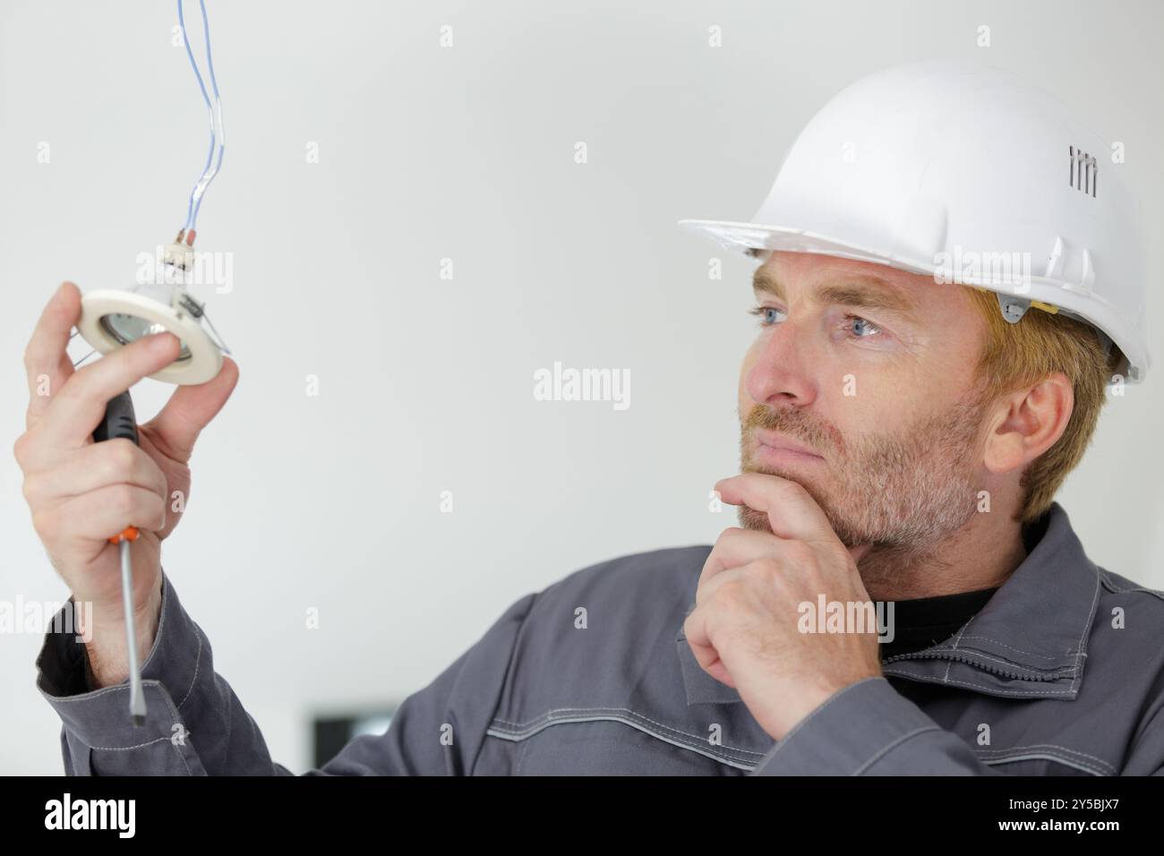 electrician man working with wires mounting lights in house Stock Photo ...
