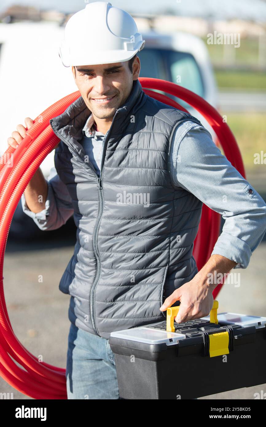 construction worker carrying hose at construction site Stock Photo - Alamy