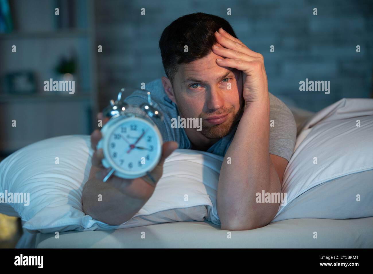 insomniac man lying in bed looking at clock Stock Photo - Alamy
