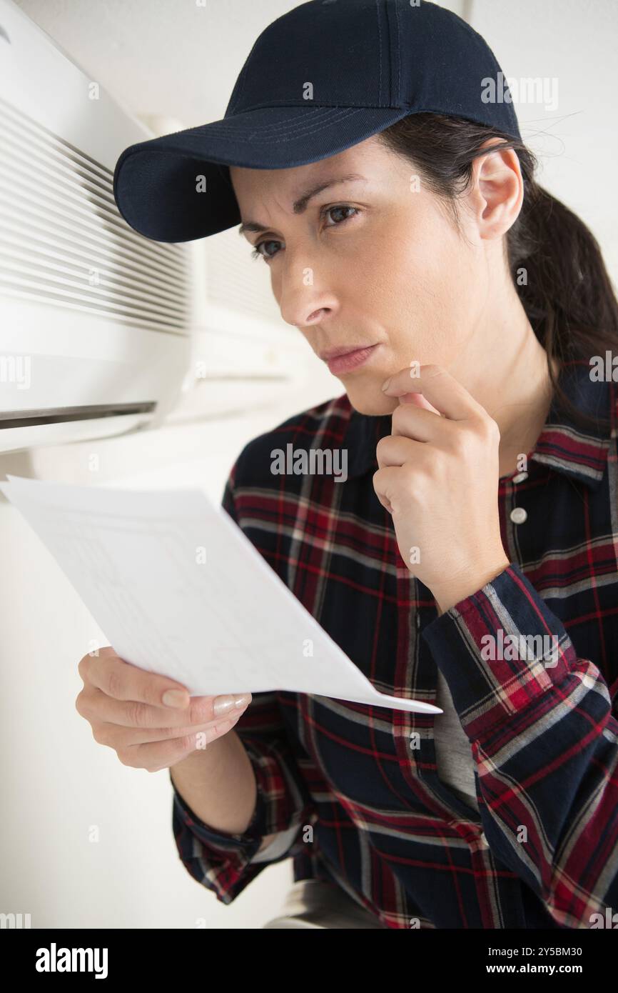 female contractor reading instructions for programming air conditioning ...