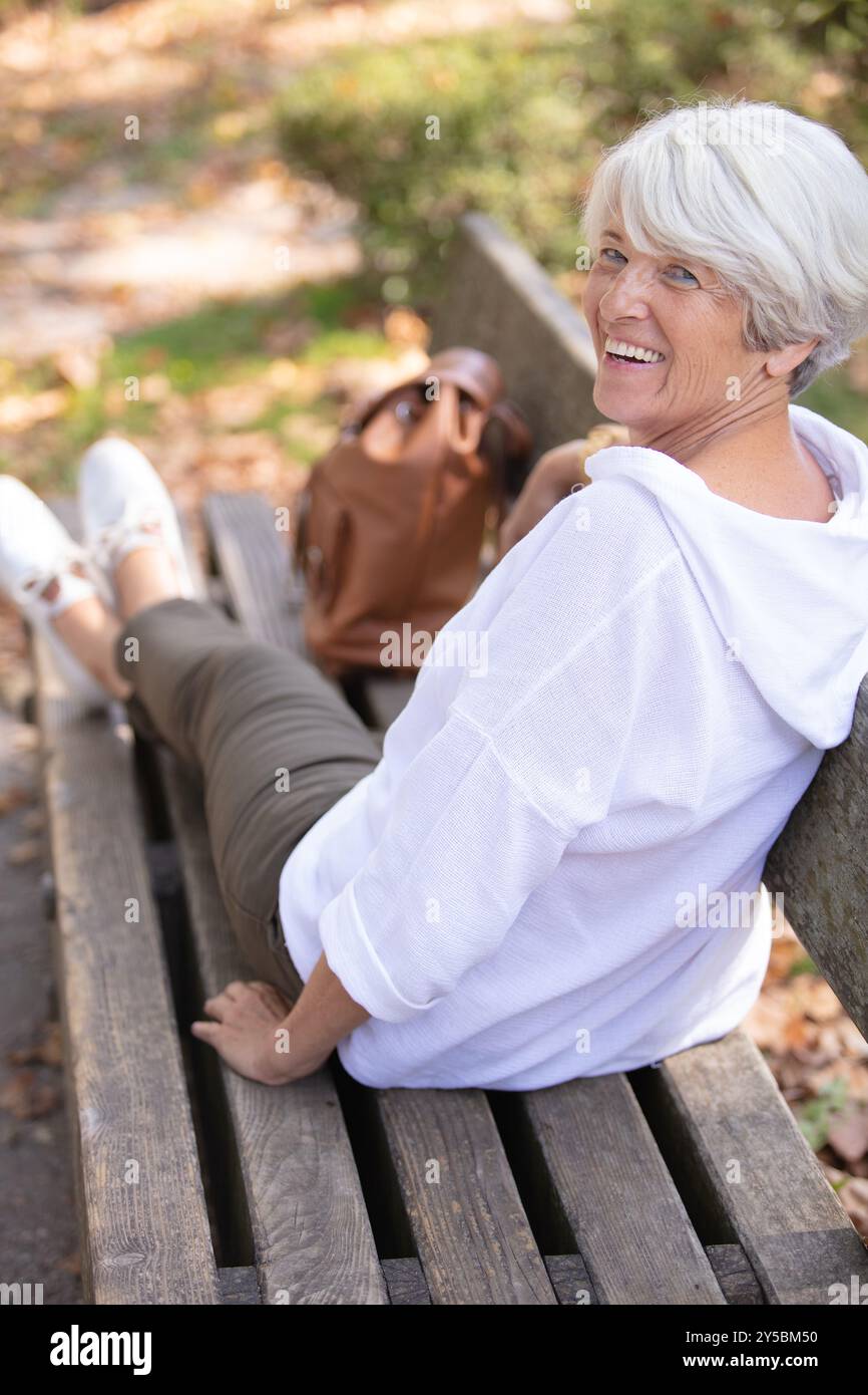 senior woman with her feet up on a park bench Stock Photo - Alamy