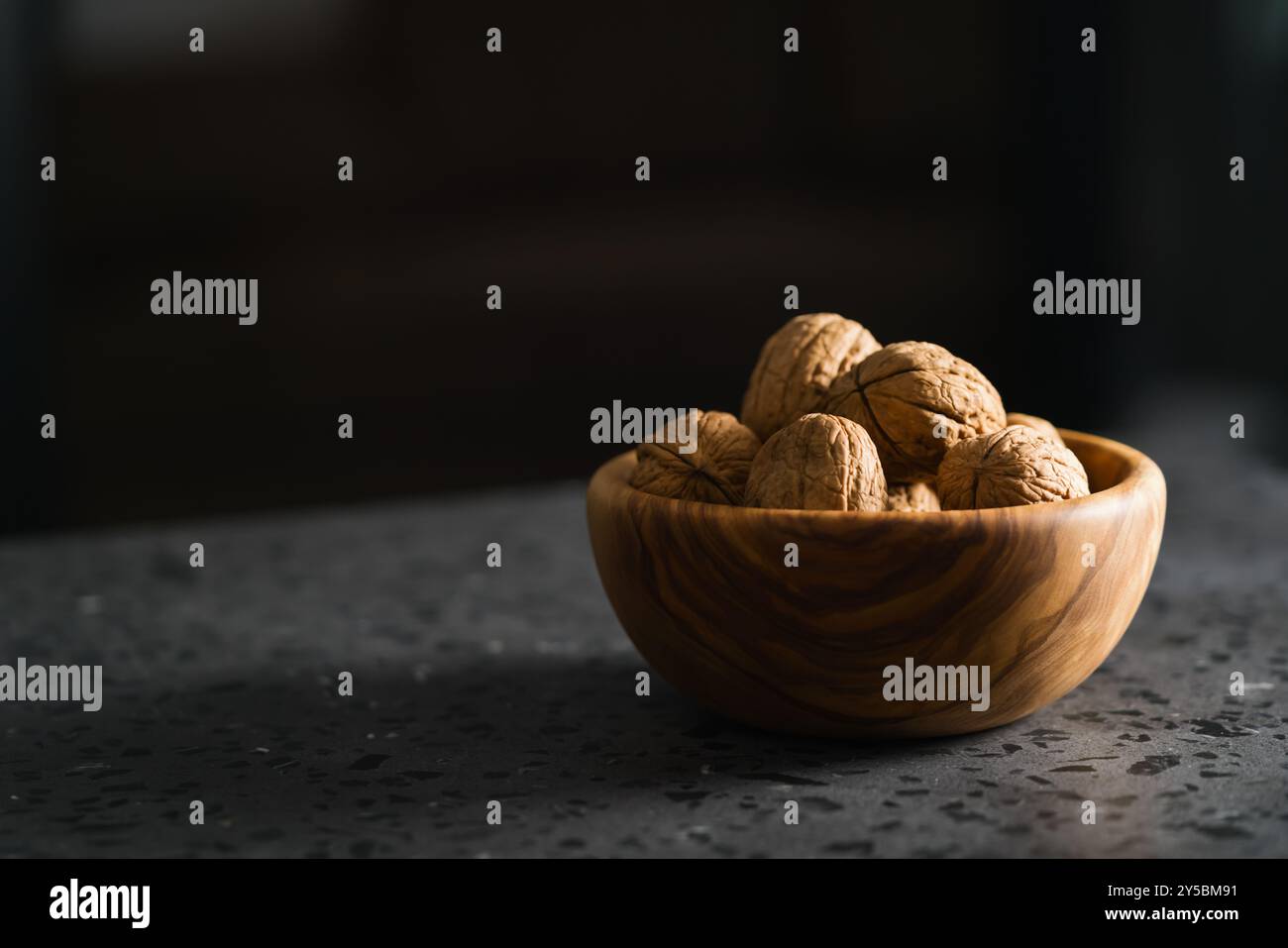 inshell walnuts in olive wood bowl on terrazzo countertop, shallow ...