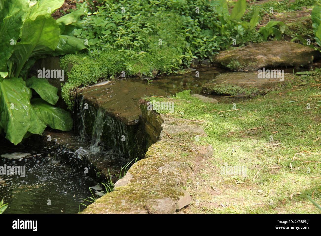 A Gentle Flow of a Stream Over a Garden Waterfall Stock Photo - Alamy