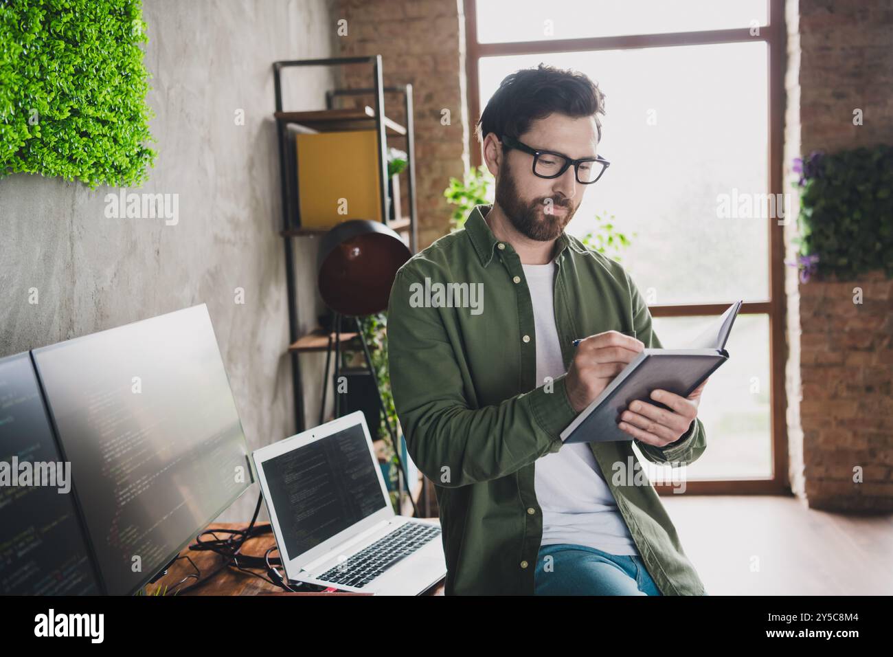 Portrait of professional hacker young man write notebook computer desk ...