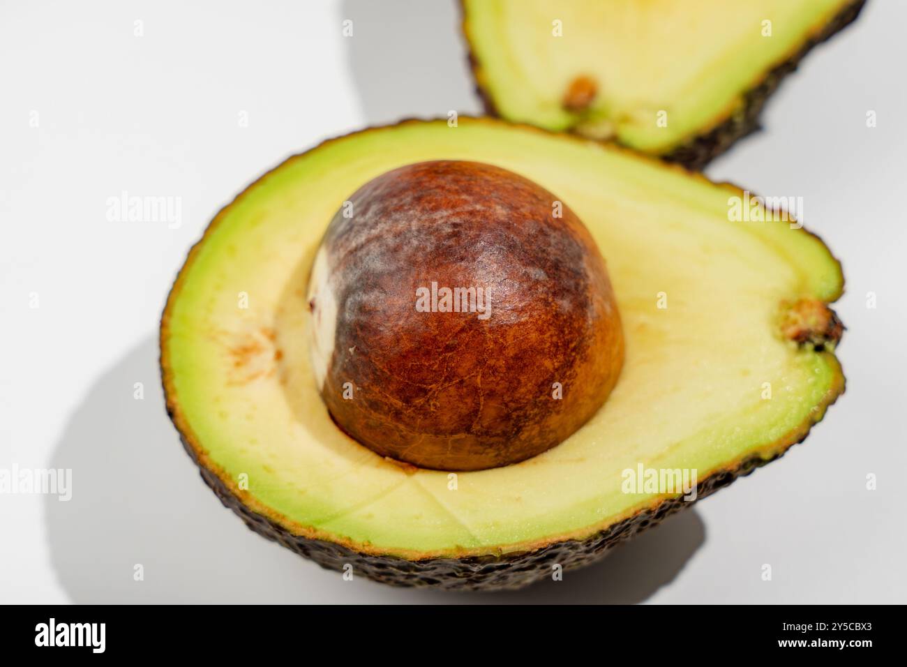 Avocado with brown pit. The avocado is cut in half and the pit is ...