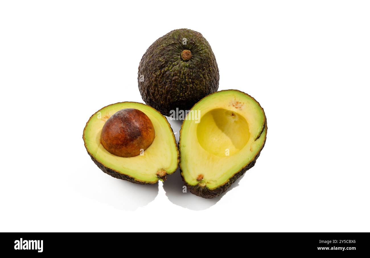 An avocado lies on a white background. The avocado is cut in half ...