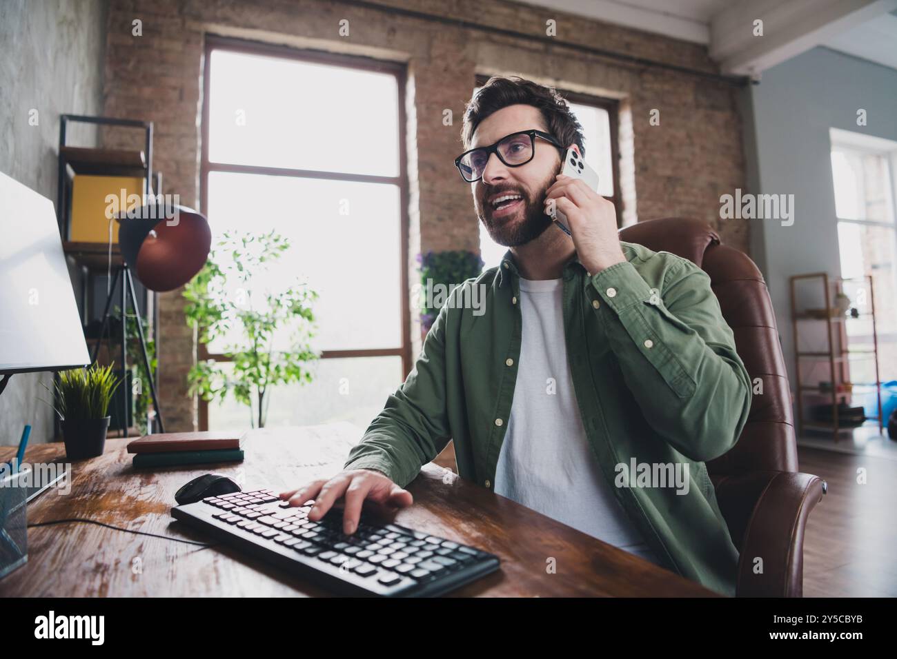 Portrait of professional hacker young man sit chair speak phone ...
