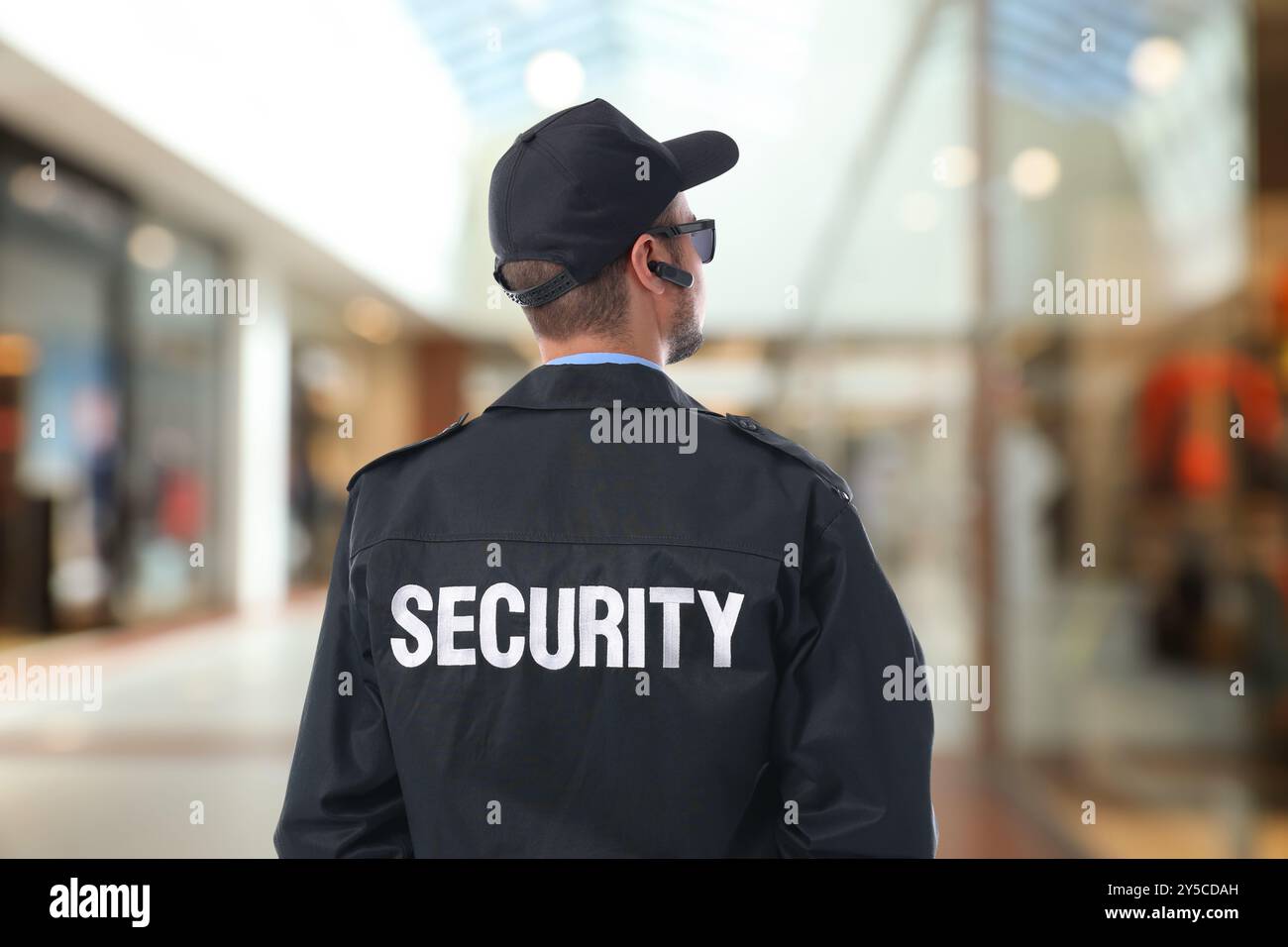 Security guard in uniform and earpiece in shopping mall, back view ...