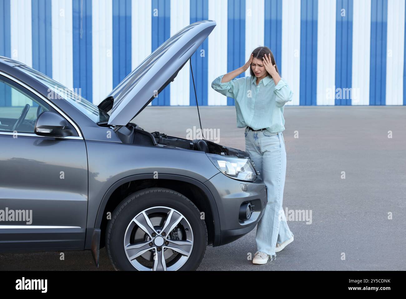Stressed woman looking under hood of broken car outdoors Stock Photo - Alamy