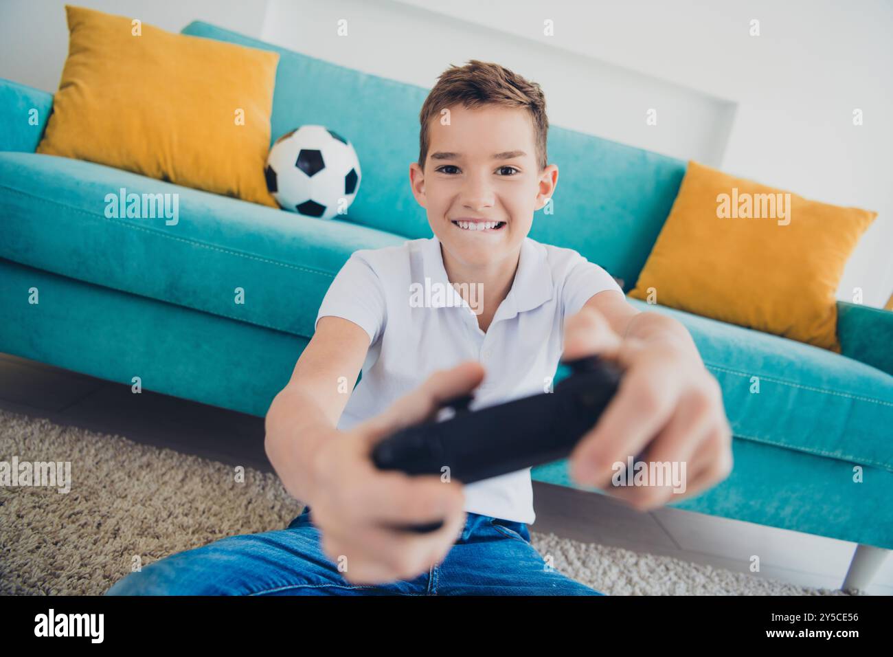 Portrait of charming little boy bite lips play game controller wear t ...