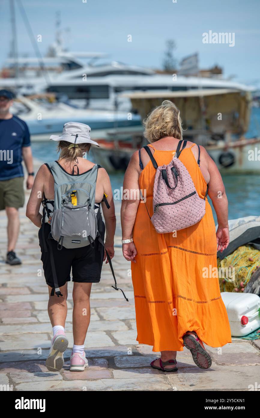 Large lady wearing bright orange dress walking with a friend on holiday ...