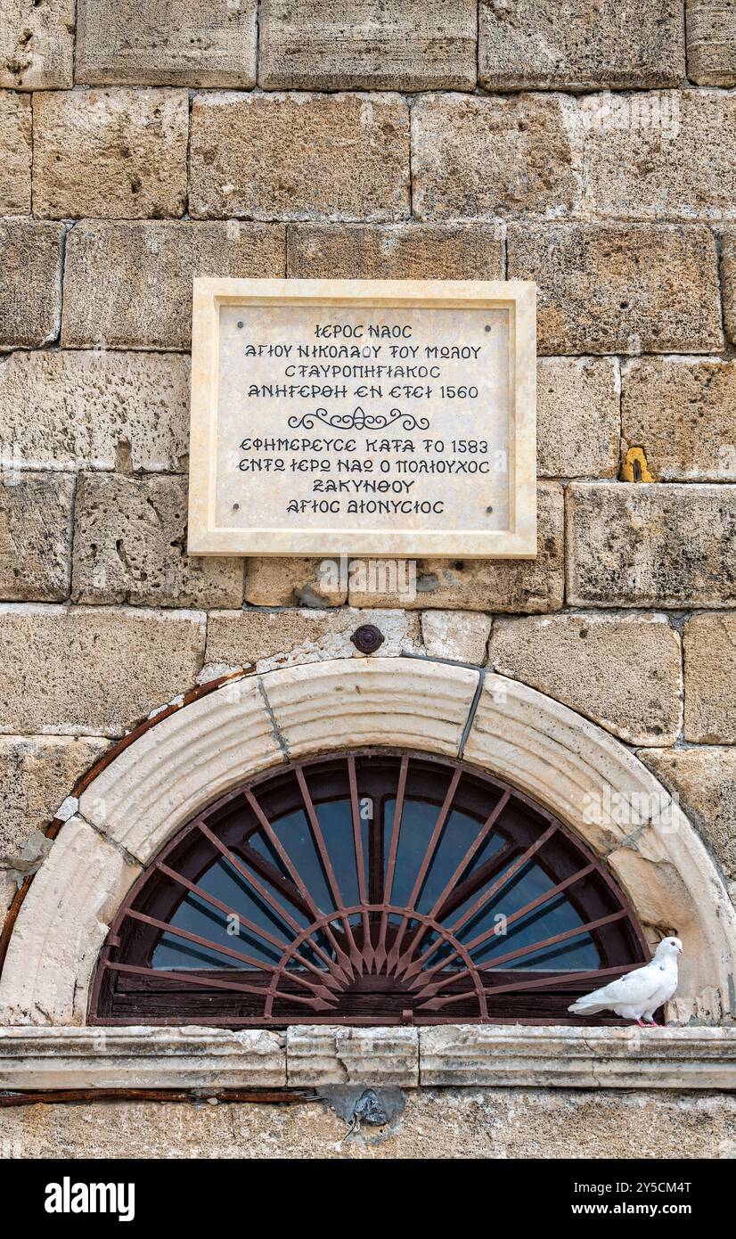 white dove sitting next to arched window and commemorative plaque above ...