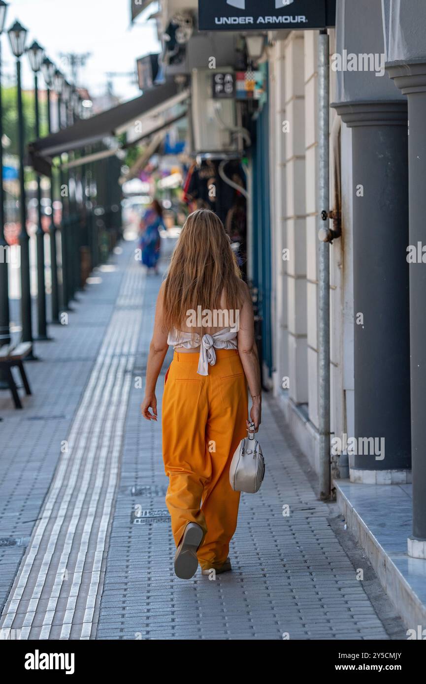attractive young woman walking along a street alone, female with red ...