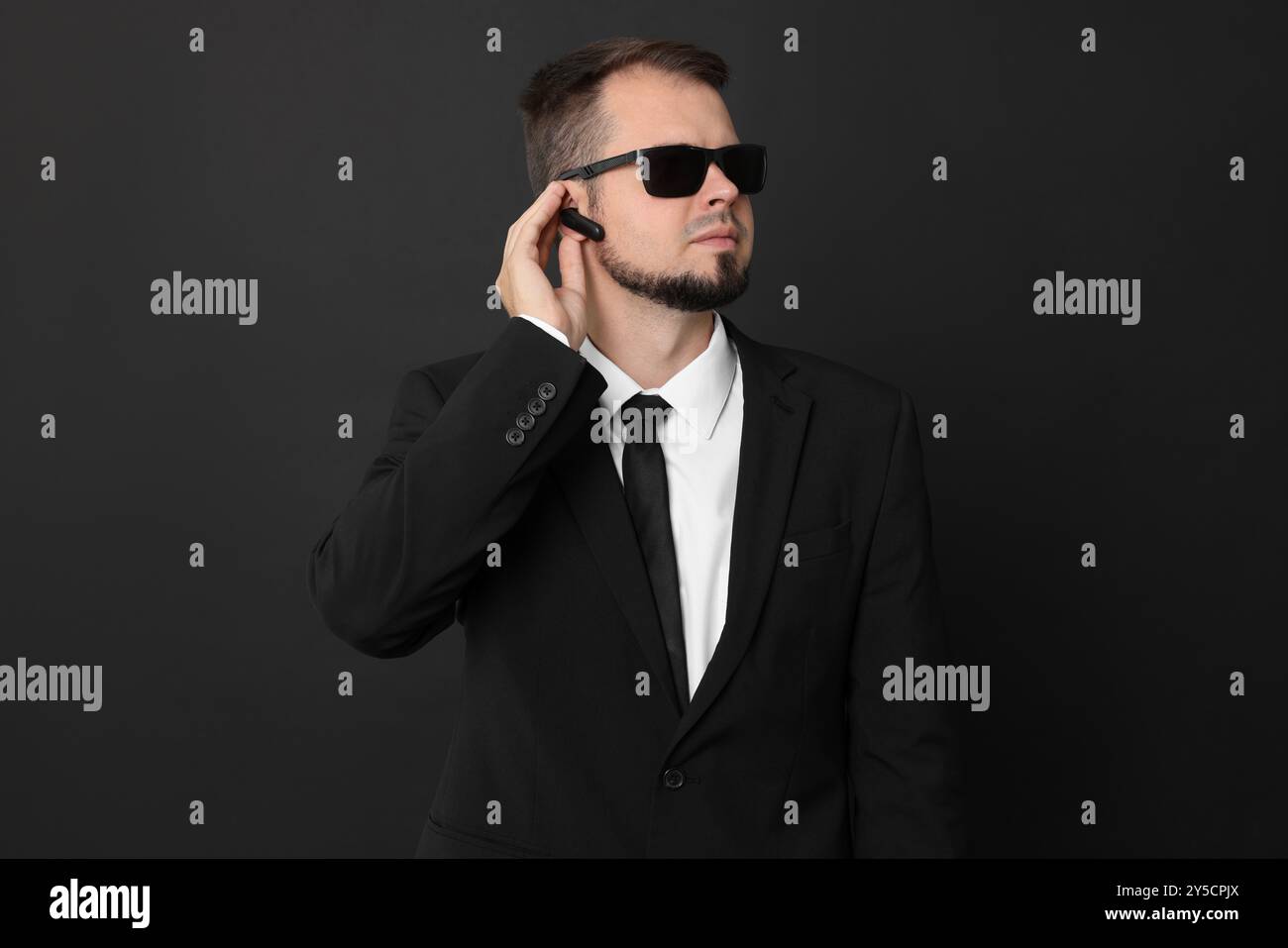 Young bodyguard in suit with sunglasses on black background Stock Photo ...