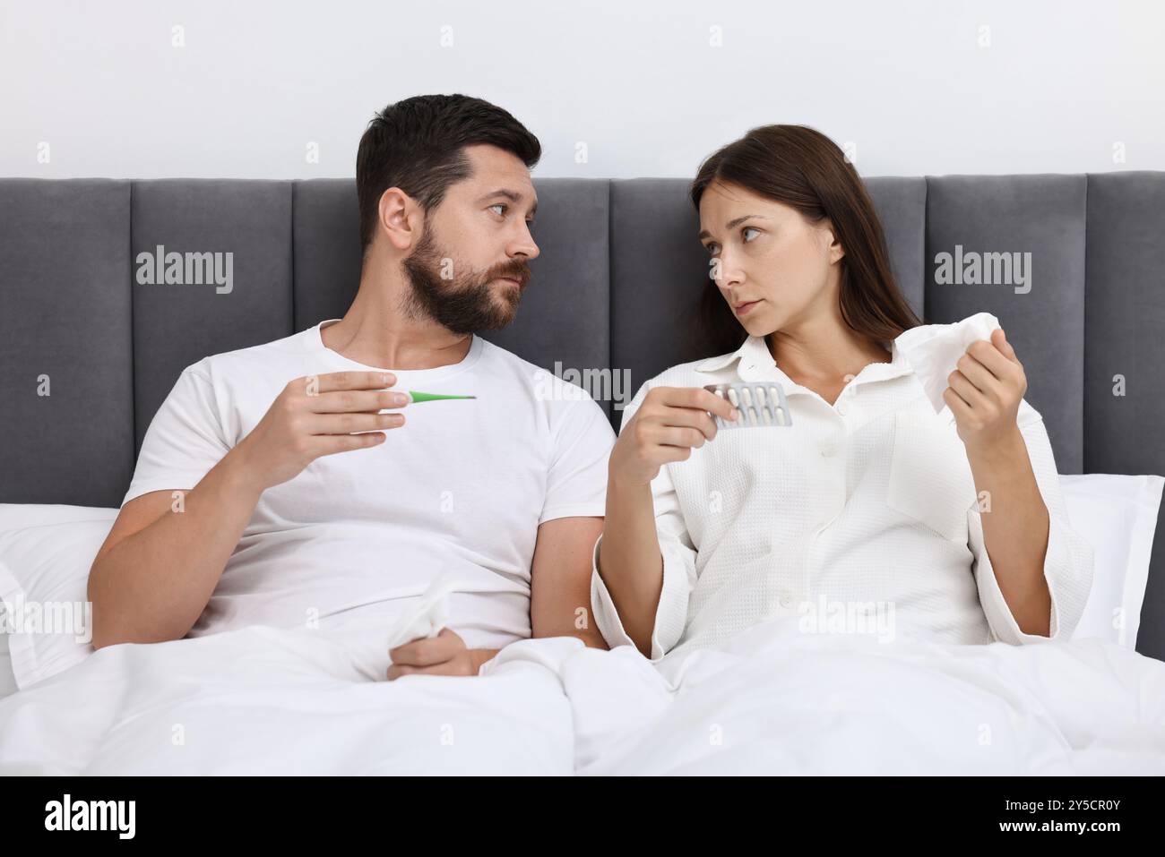 Cold symptom. Couple suffering from fever in bed at home Stock Photo ...